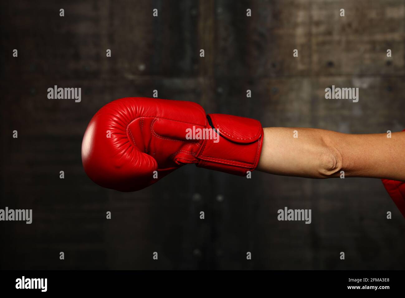 Woman hand in red boxing glove punching over dark background, close up ...