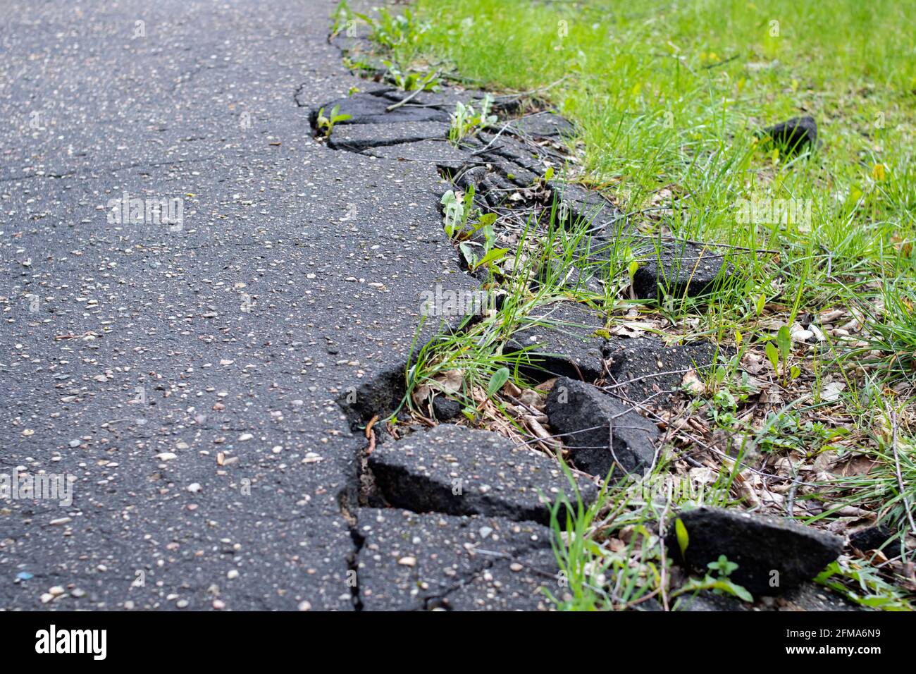 Broken asphalt pavement and green grass close up Stock Photo - Alamy
