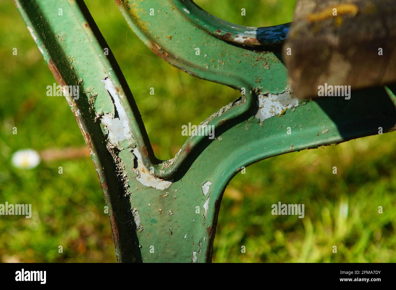 Details of a rusty bench in a park. The paint is peeling, it is rusting ...