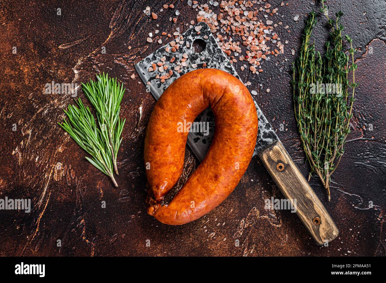 Hot Smoked sausage on a butcher rustic cleaver with herbs. Dark ...