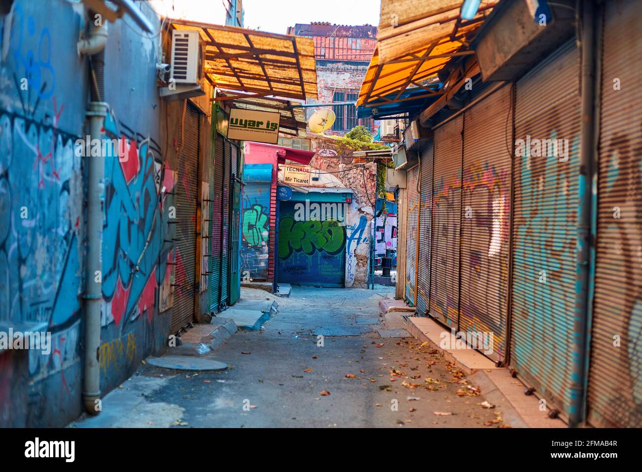 Narrow market street covered with graffiti. The roller shutters of the ...