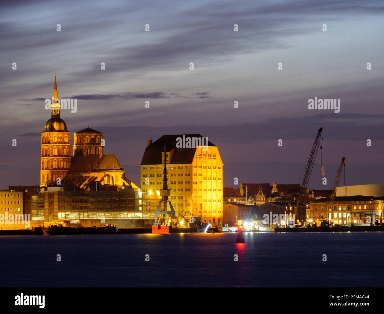 View over sea to old town silhouette of Stralsund and harbor at dusk ...