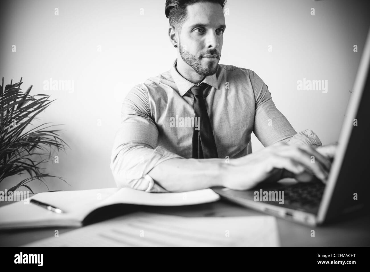 Young man sitting desk working Black and White Stock Photos & Images ...