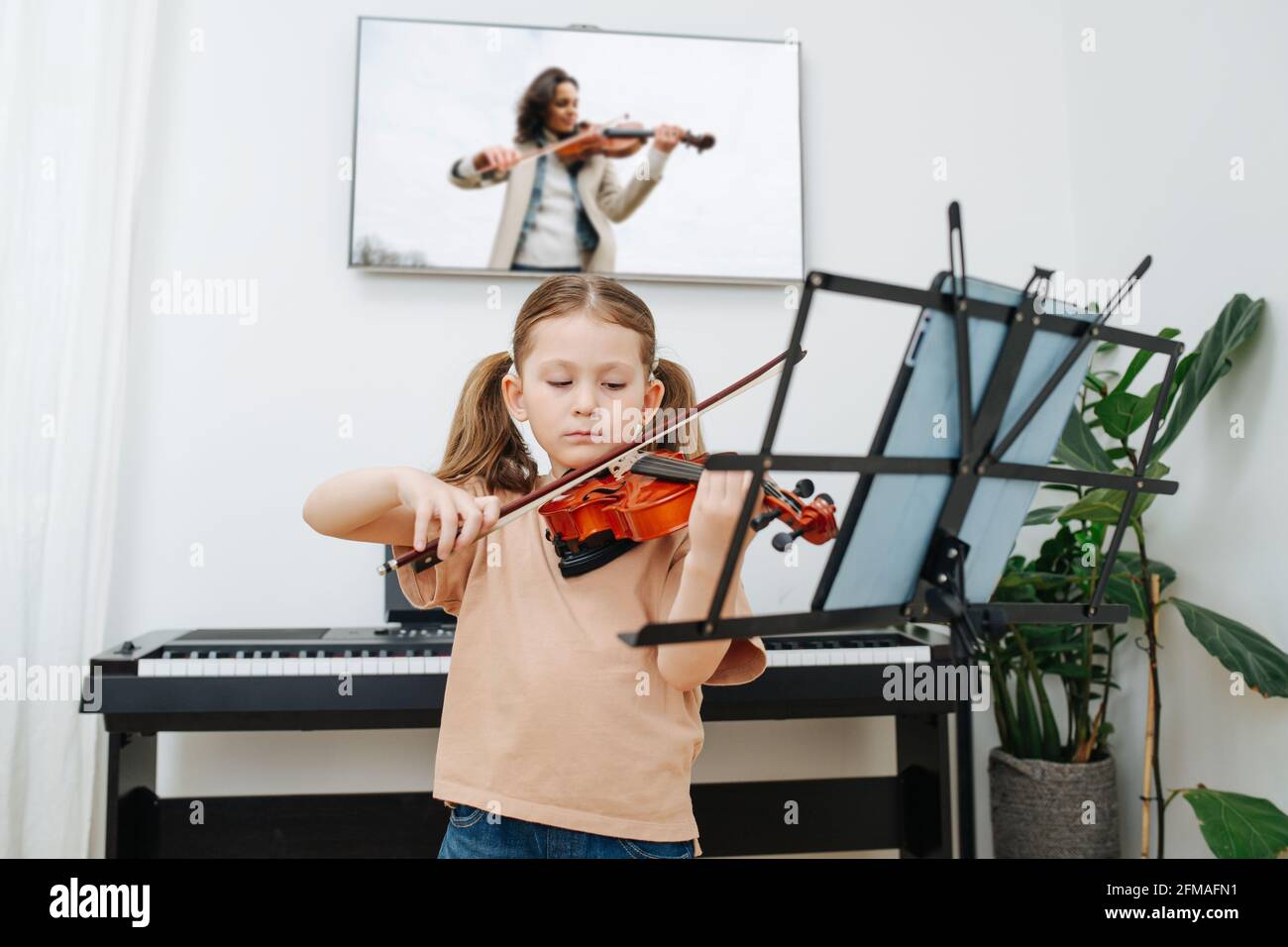 Adorable little girl with two pony tails learning to play violin ...
