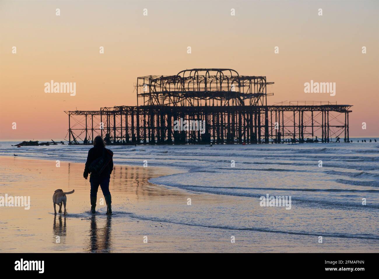Taking the dog for a walk on the beach at low tide. The silhouetted ...