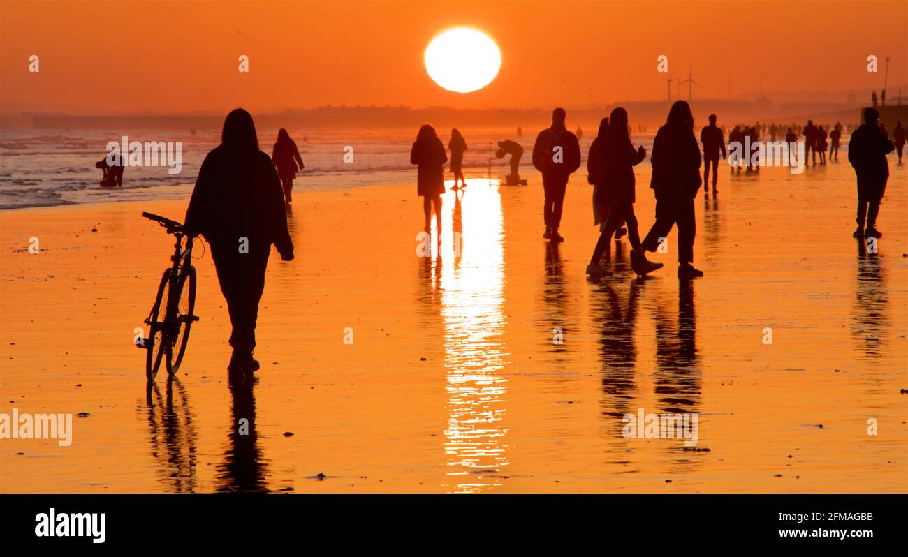 Brighton and Hove beach at low tide looking west. Silhouettes of people ...