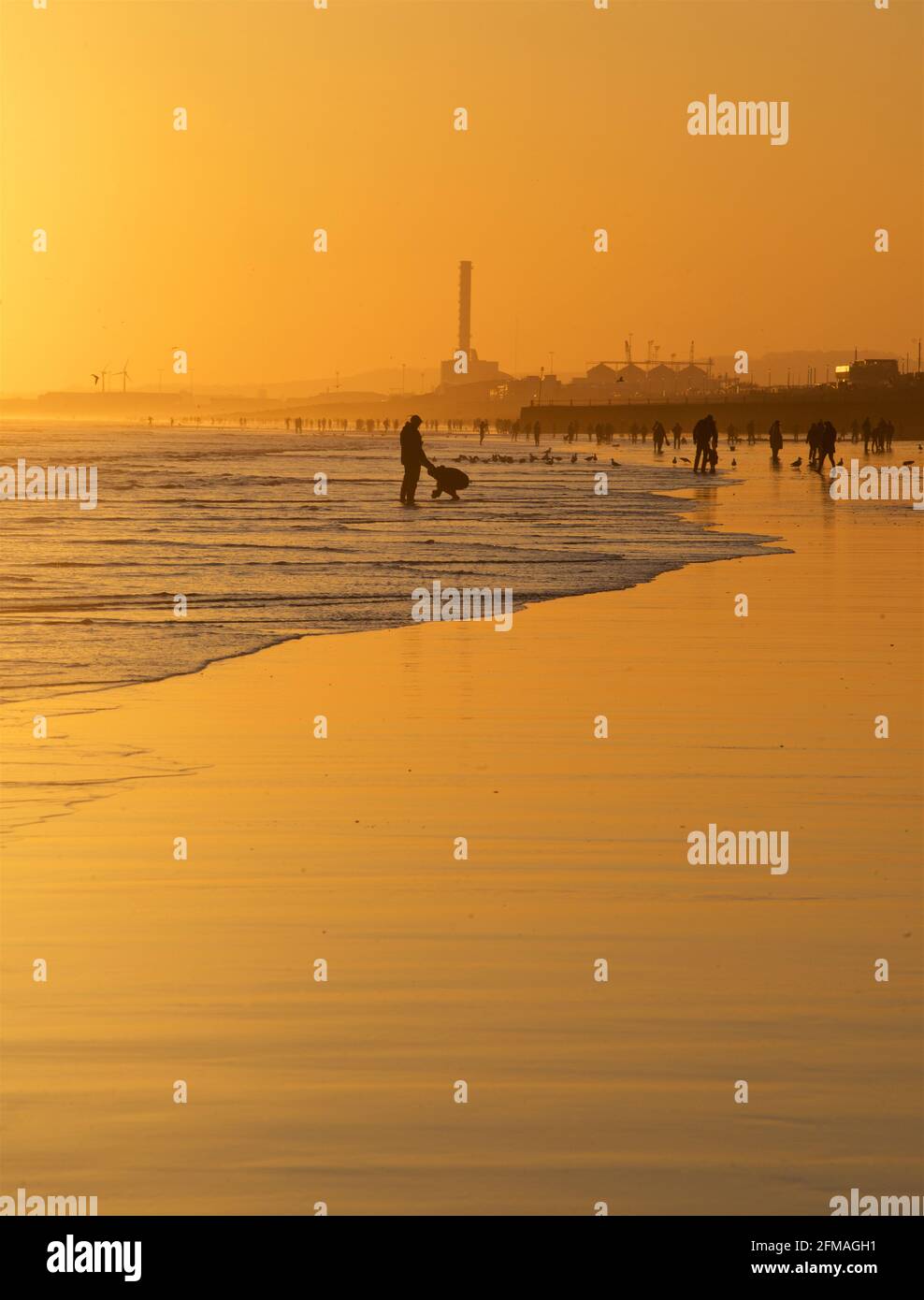 Brighton and Hove beach at low tide looking west. Silhouettes of people ...