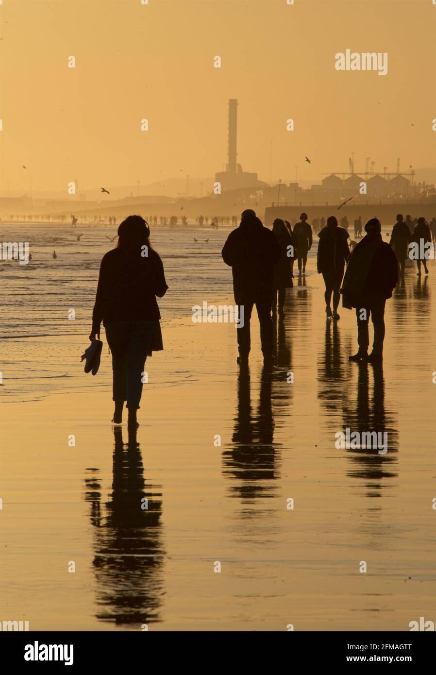 Brighton and Hove beach at low tide looking west. Silhouettes of people ...