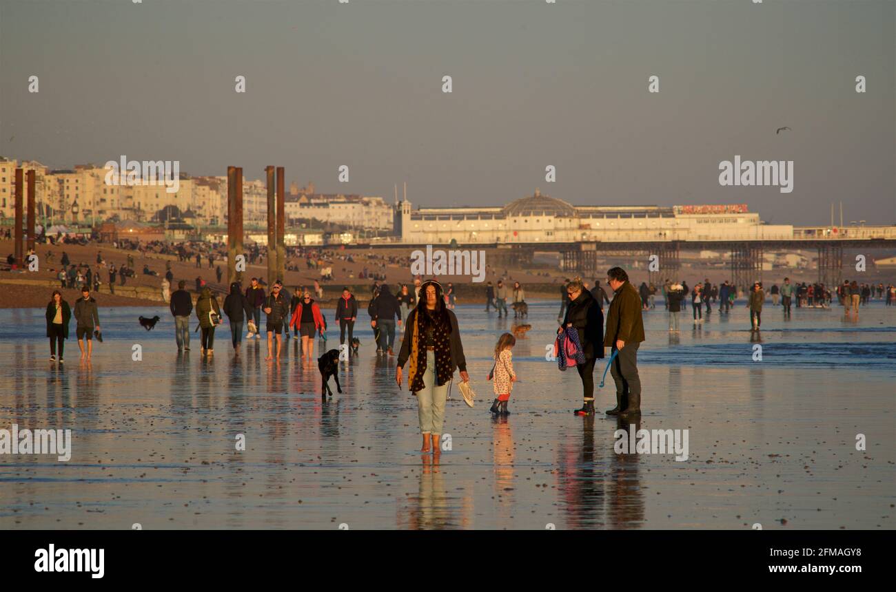 Beachgoers on Brighton beach during a low tide, late afternoon, spring ...