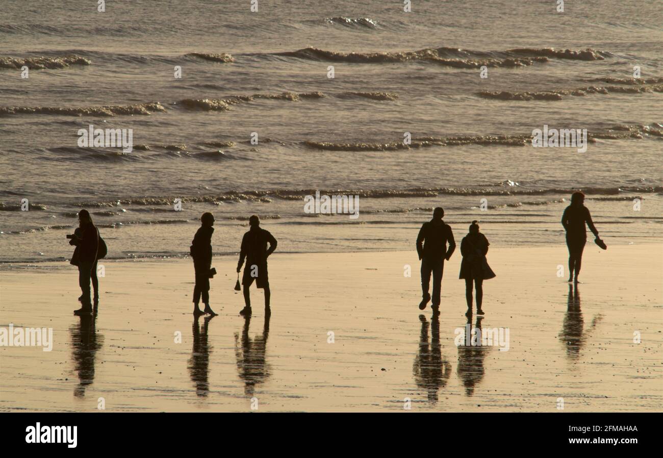 Brighton and Hove beach at low tide. Silhouettes of people walking ...