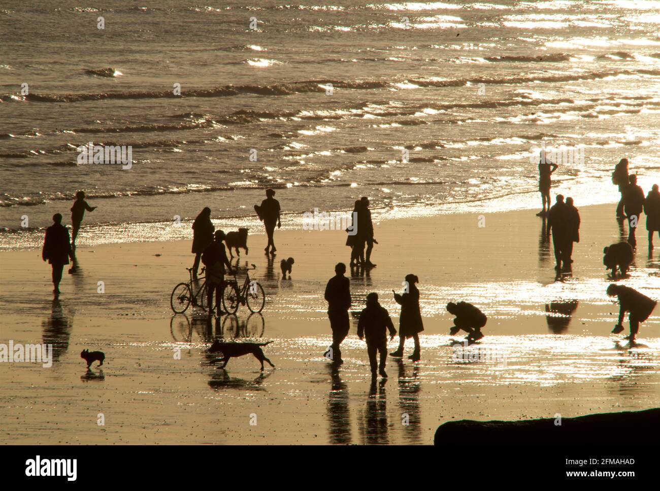 Brighton and Hove beach at low tide. Silhouettes of people walking ...