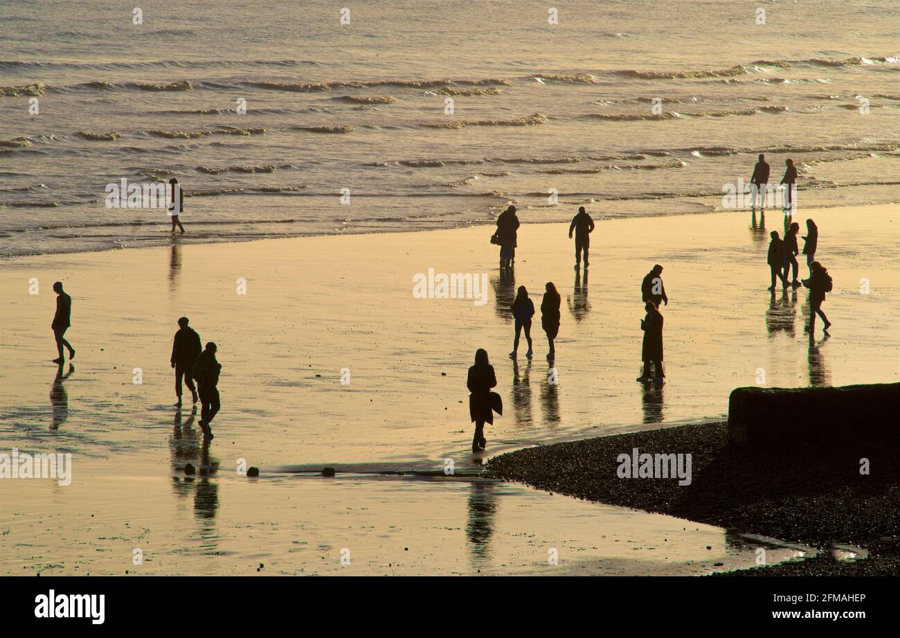 Brighton and Hove beach at low tide. Silhouettes of people walking ...