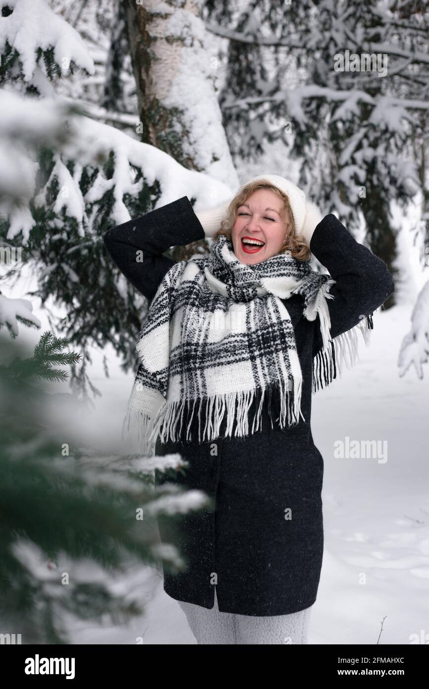 A blonde woman in winter stands under a fir-tree in the snow Stock ...