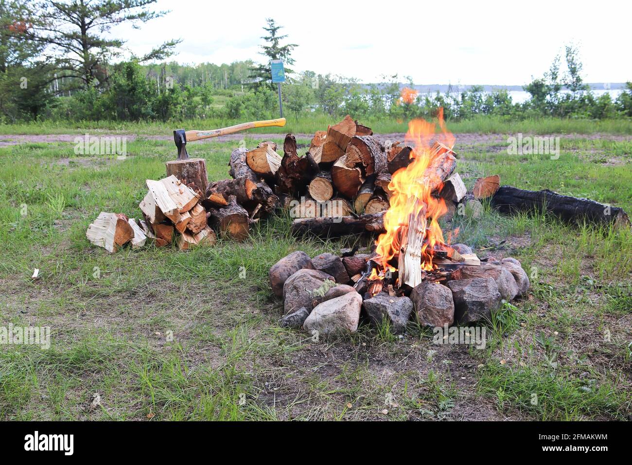 A large campfire with chopped wood behind it Stock Photo - Alamy