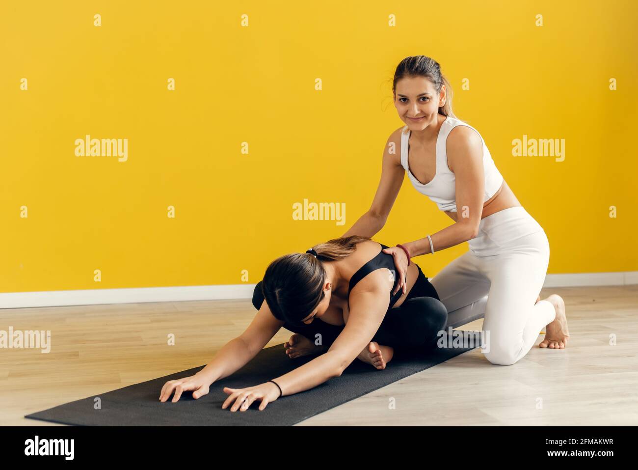 A female yoga coach controls the performance of a pose, asana ...
