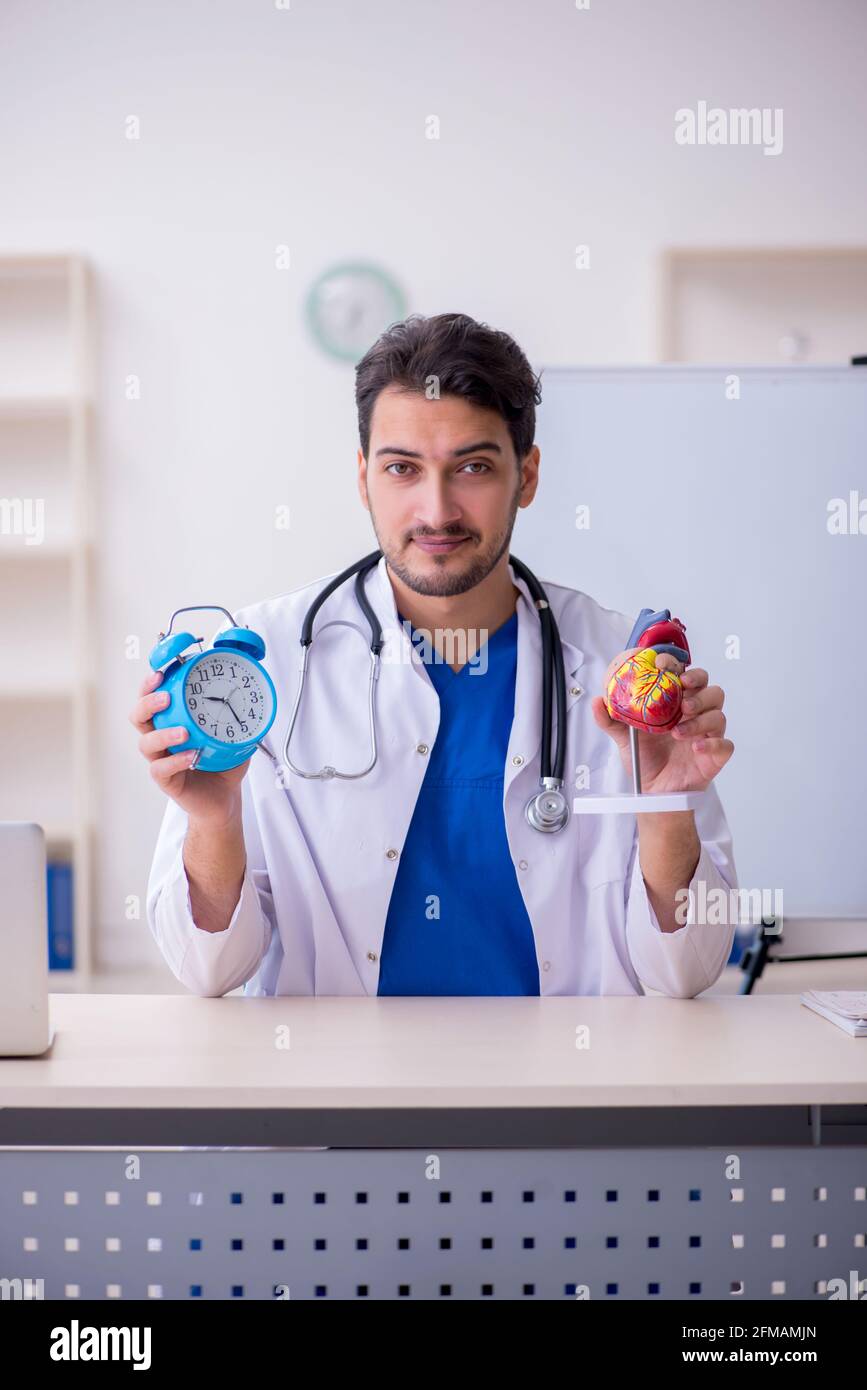 Young doctor cardiologist in time management concept Stock Photo - Alamy