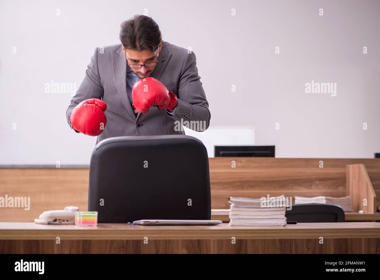 Young businessman employee wearing boxing gloves at workplace Stock ...