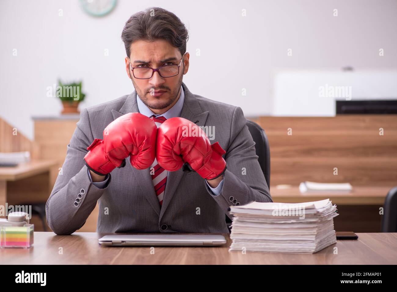 Young businessman employee wearing boxing gloves at workplace Stock ...