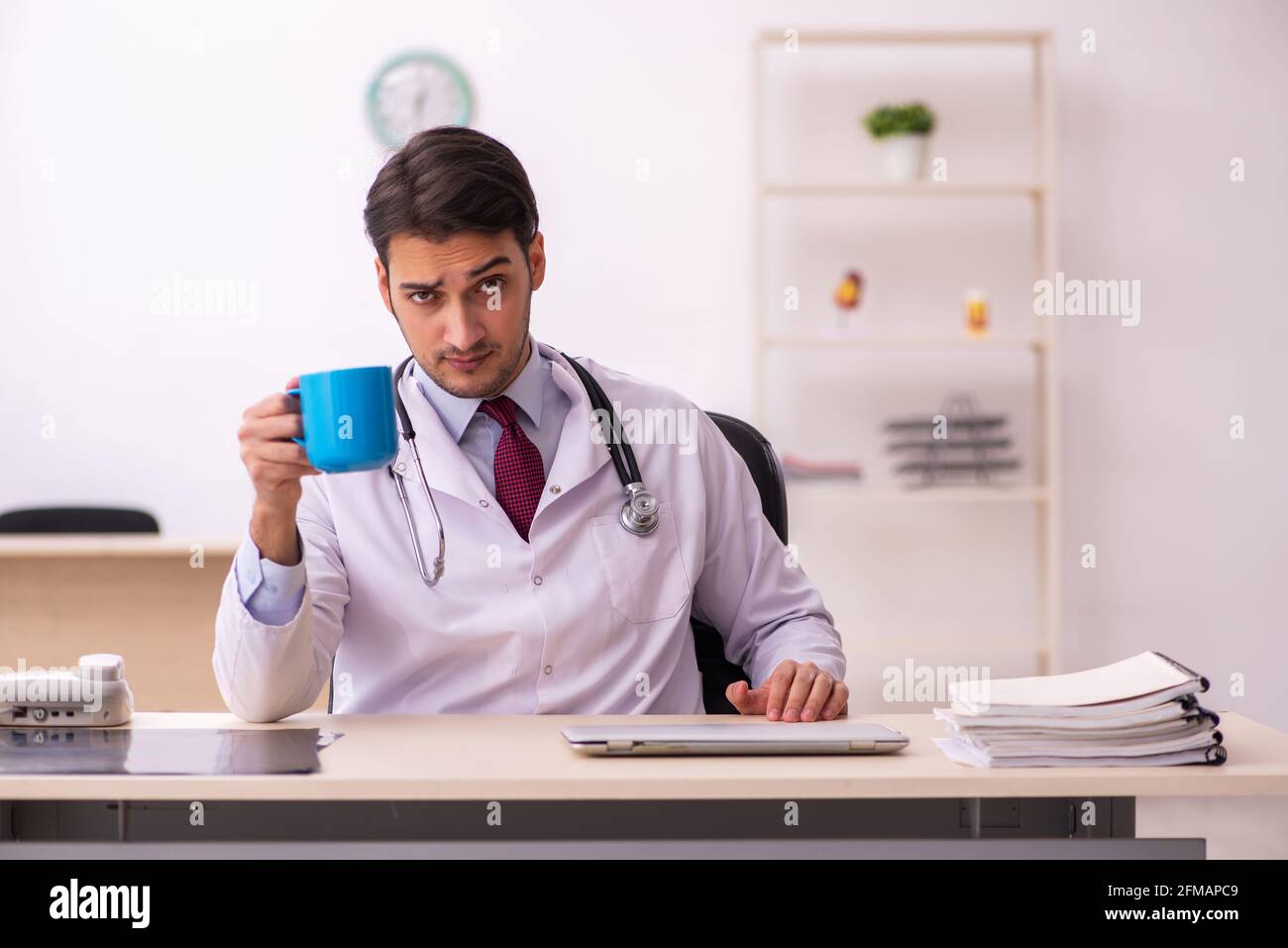Young male doctor drinking coffee at the hospital Stock Photo - Alamy