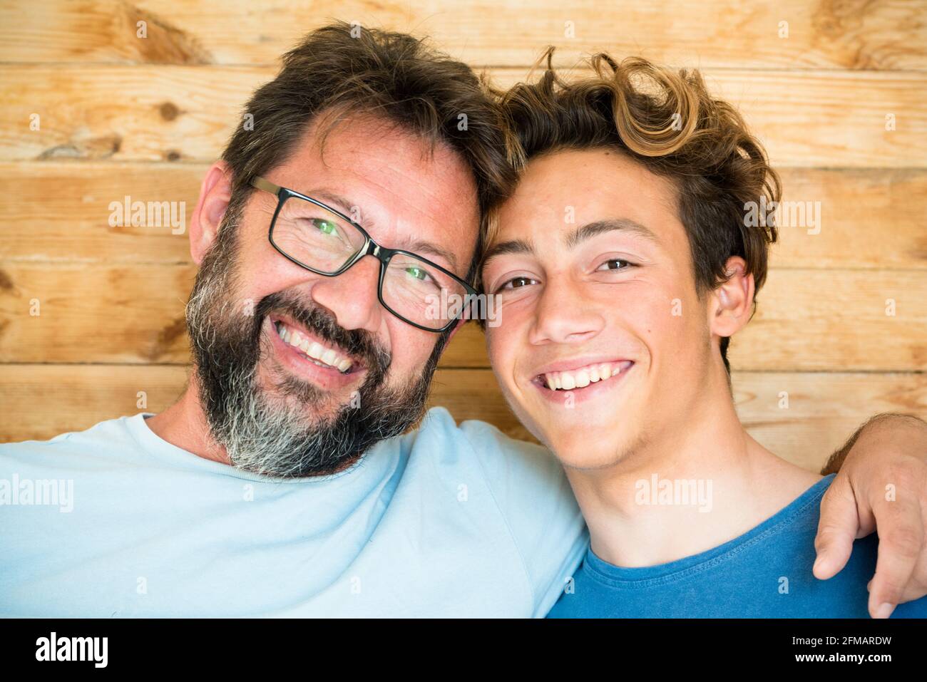 Head shot happy teenager son embracing shoulders of happy middle aged ...
