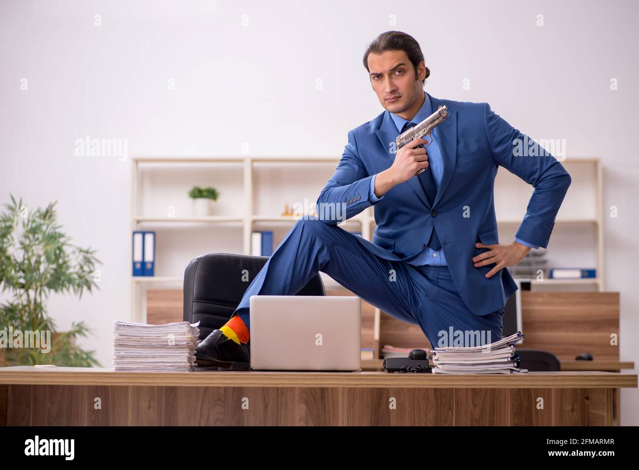 Young businessman employee holding gun at workplace Stock Photo - Alamy