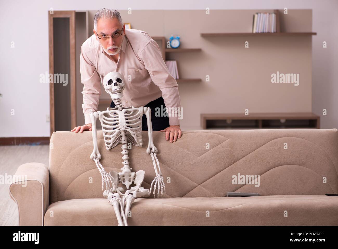 Old man sitting on the sofa with the female skeleton in undying love ...
