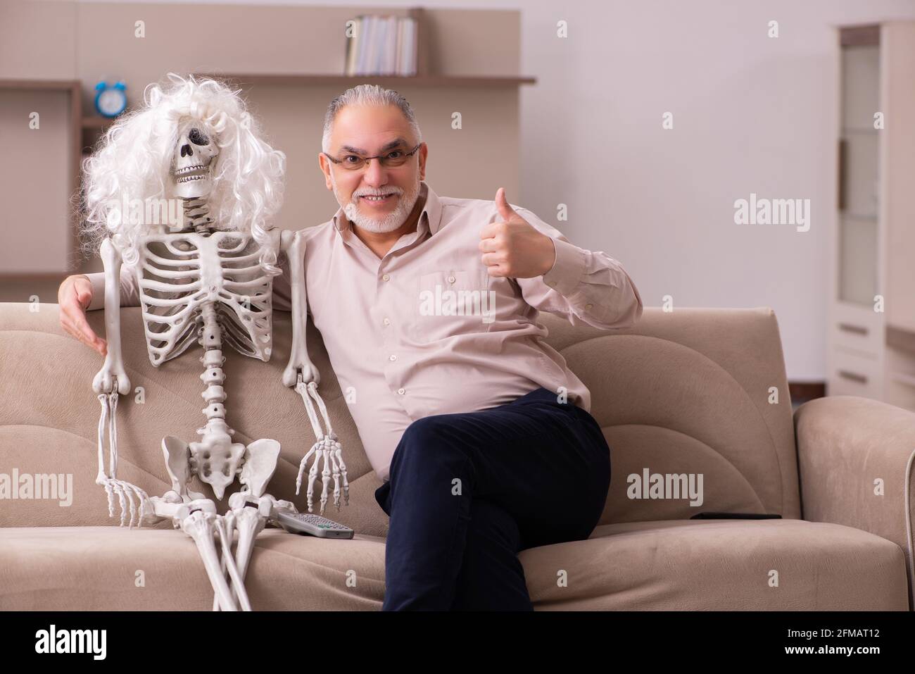 Old man sitting on the sofa with the female skeleton in undying love ...