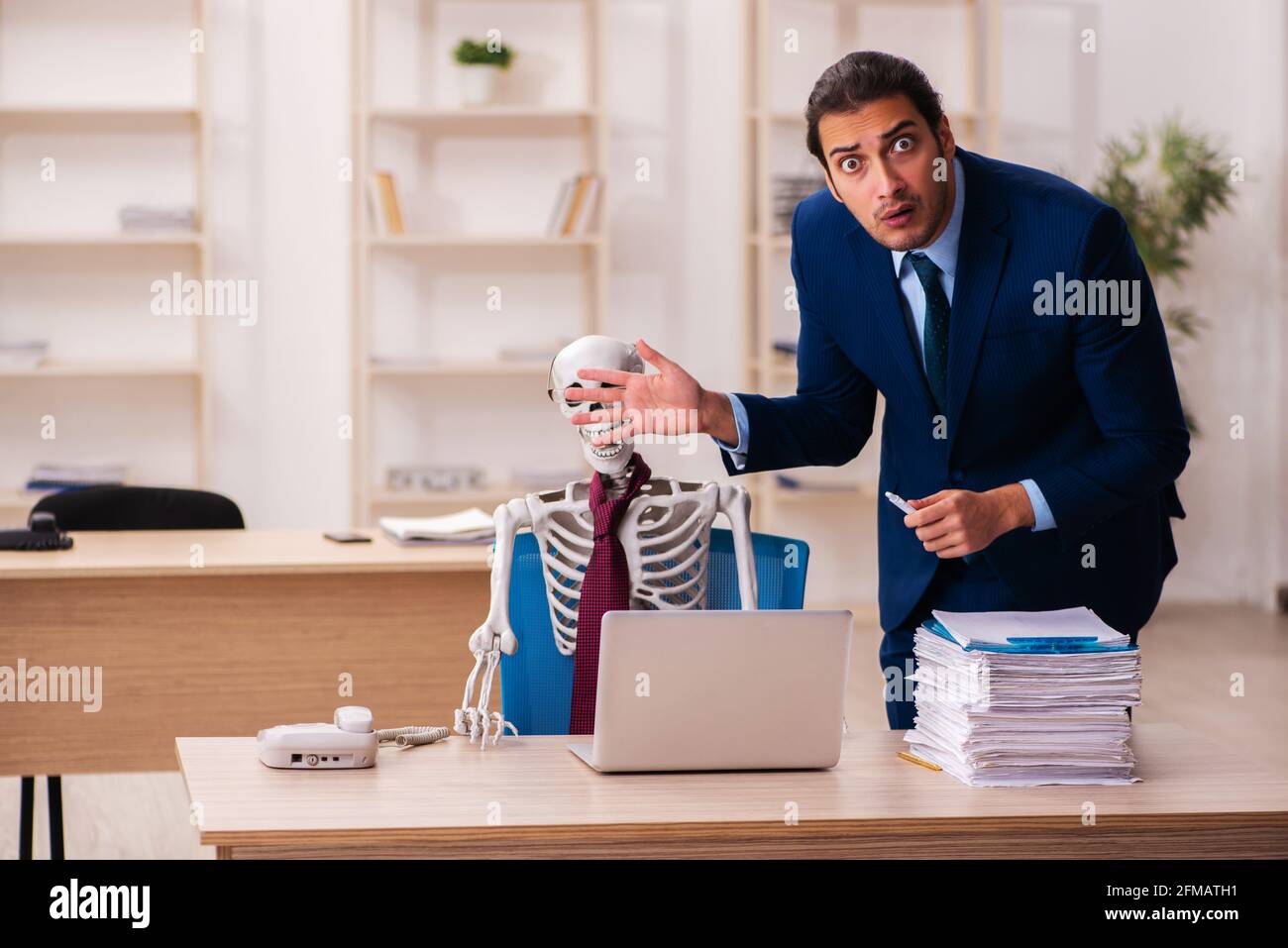 Dead employee working in the office in funny concept Stock Photo - Alamy