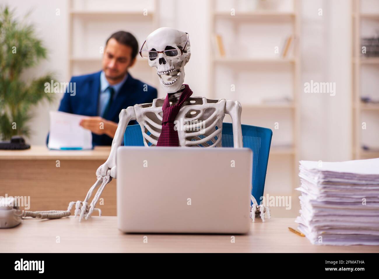 Dead employee working in the office in funny concept Stock Photo - Alamy