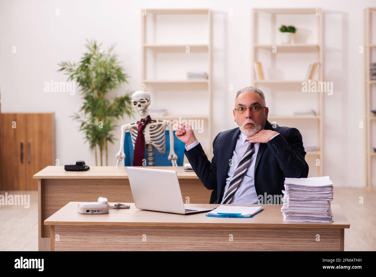 Dead employee working in the office in funny concept Stock Photo - Alamy