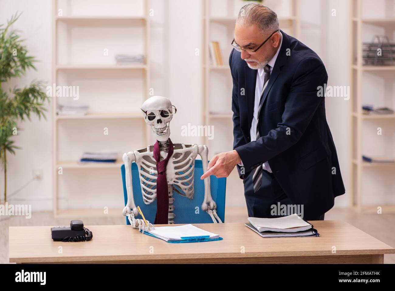 Dead employee working in the office in funny concept Stock Photo - Alamy