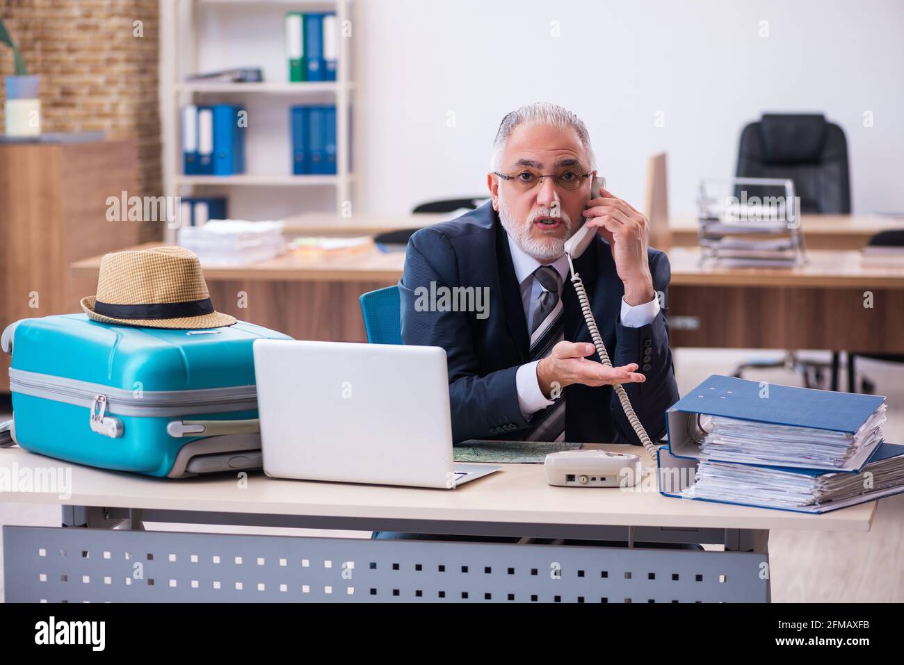 Aged male employee preparing for travel in the office Stock Photo - Alamy