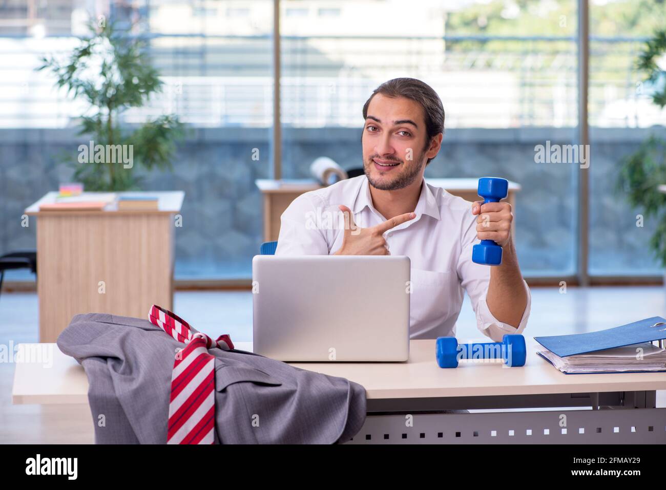 Young employee doing sport exercises at workplace Stock Photo - Alamy