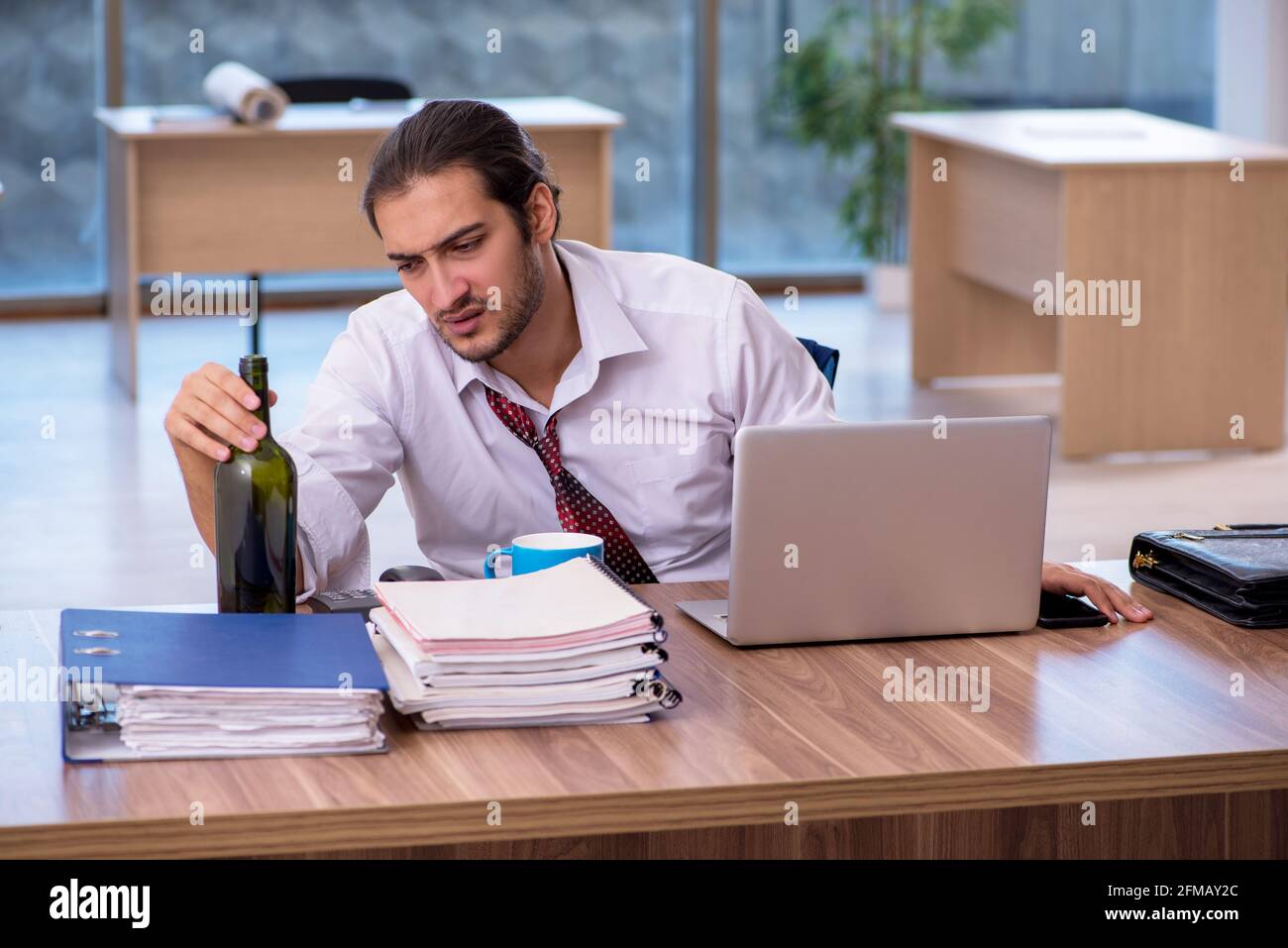 Young alcohol addicted employee working in the office Stock Photo - Alamy