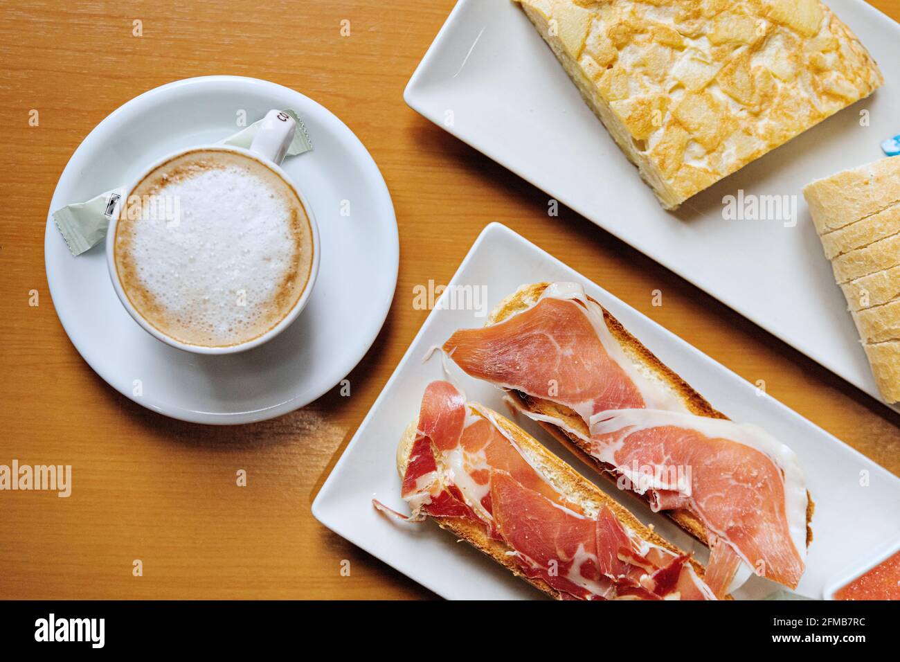 Top view of a cup of cappuccino with bread and ham slices on a plate ...