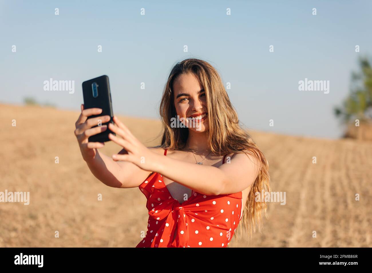 Low angle shot of a young attractive Caucasian female taking a selfie ...