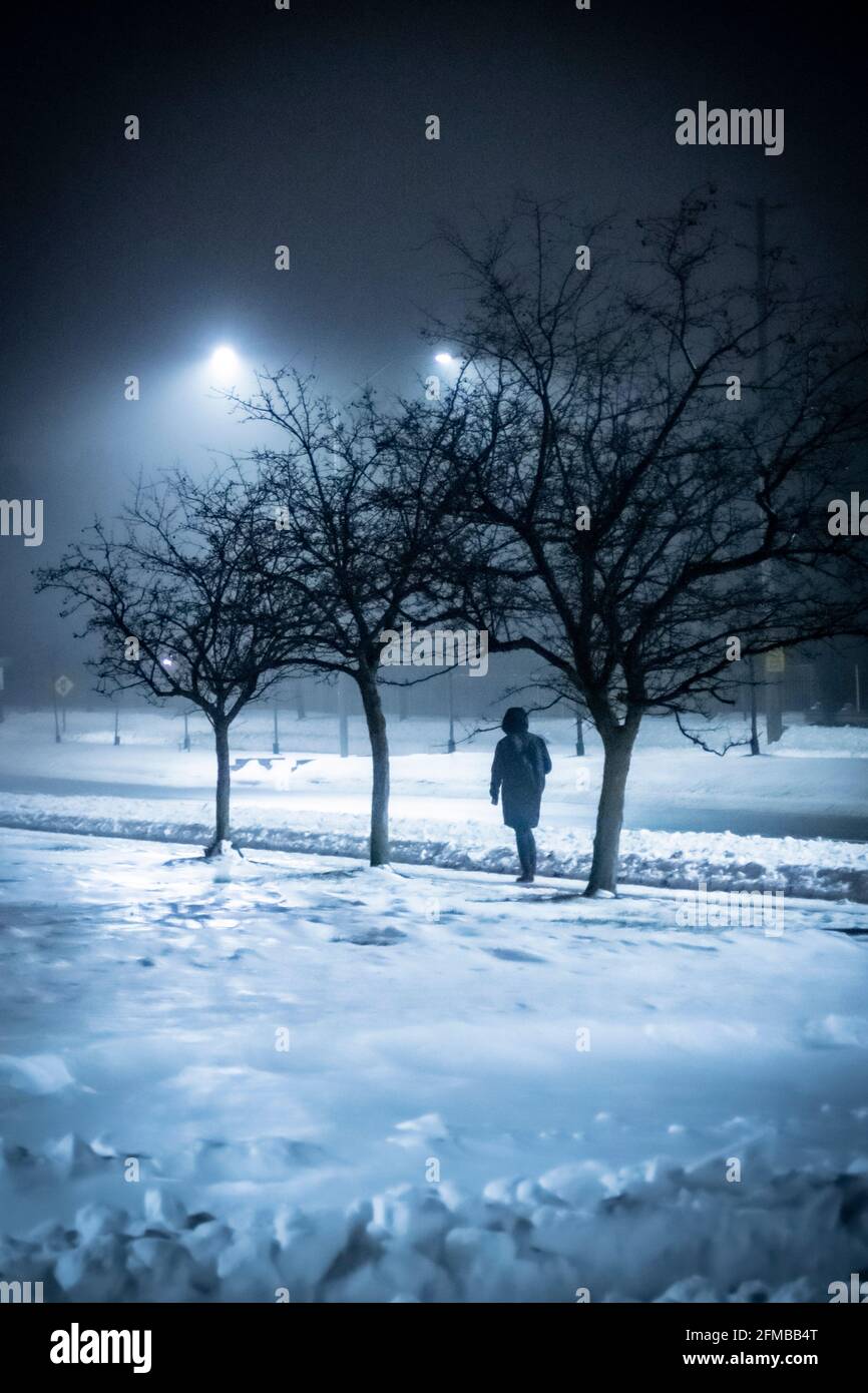 Pedestrian walking along a road on a snowy night Stock Photo - Alamy