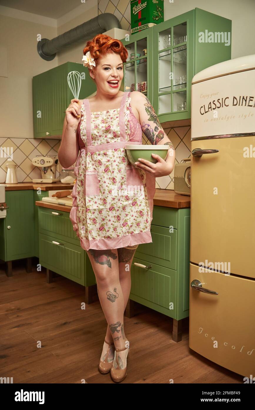 Pin-up girl with red hair baking in the kitchen Stock Photo - Alamy