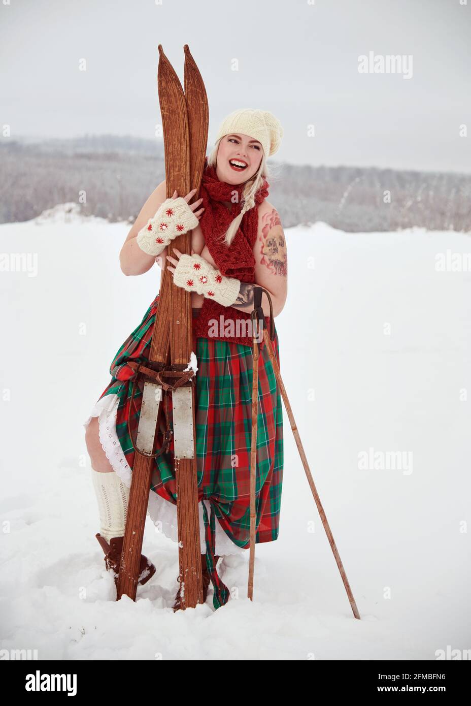 Blond curvy model with old wooden skis in the snow Stock Photo - Alamy