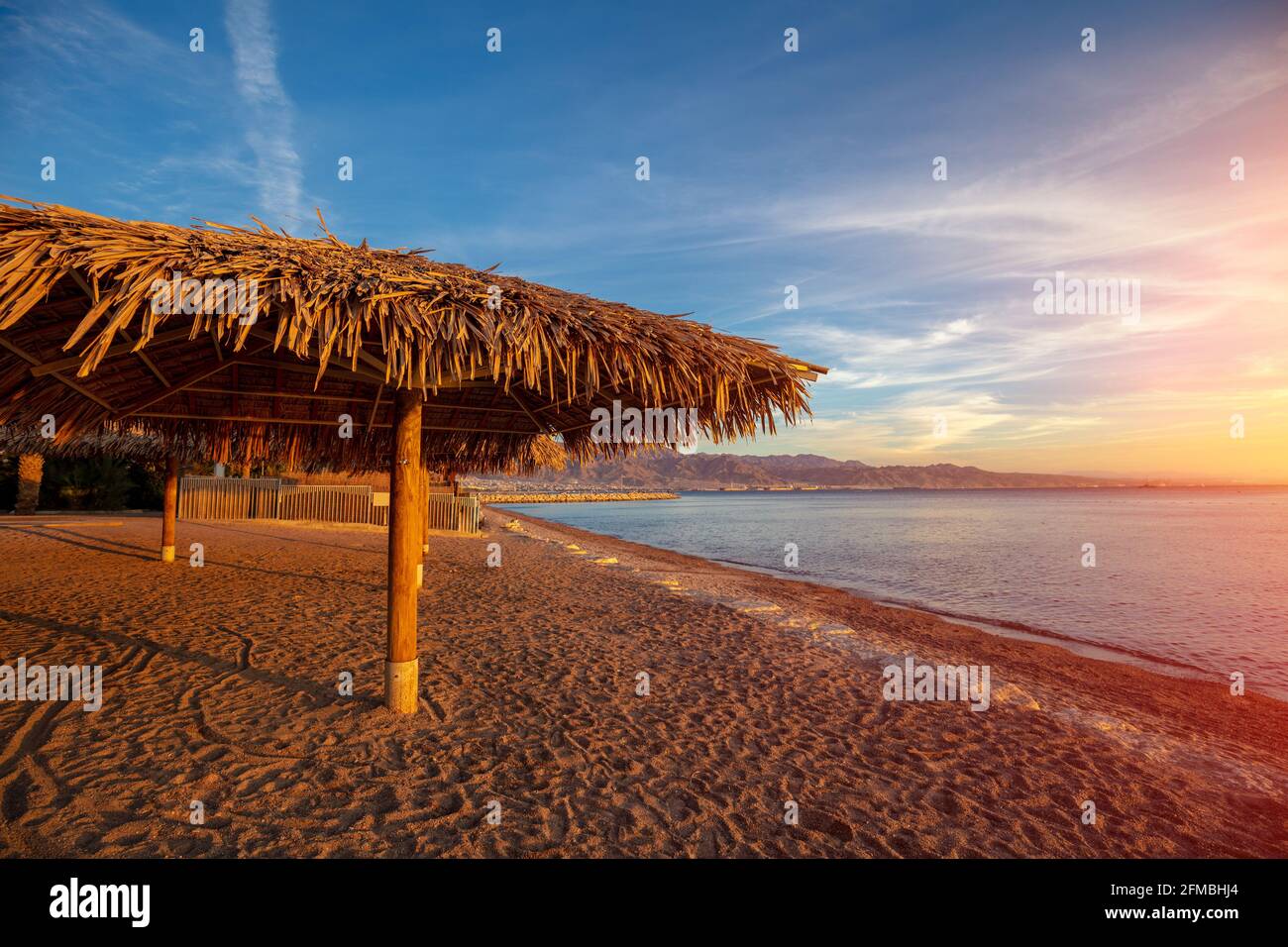 Tropical beach scenery with sun parasols. Straw sun umbrellas on the ...