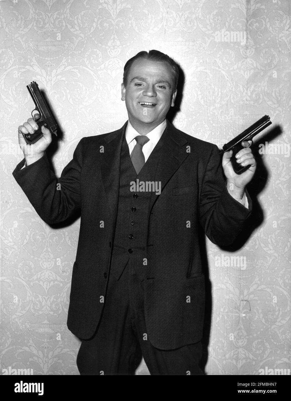 JAMES CAGNEY on set candid portrait holding two guns during filming of ...