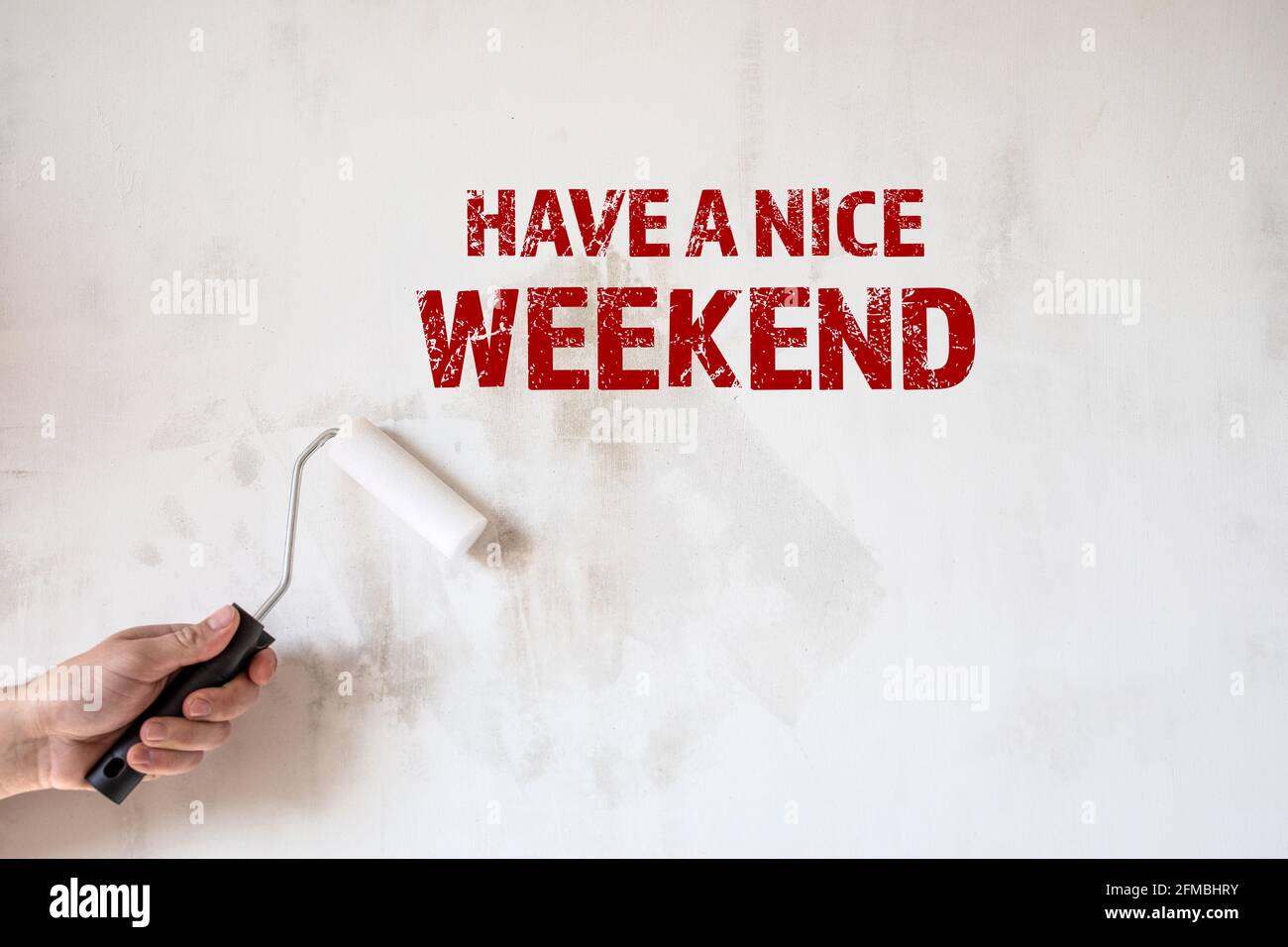 Have a nice Weekend. Paint roller in a man's hand. Concrete wall ...