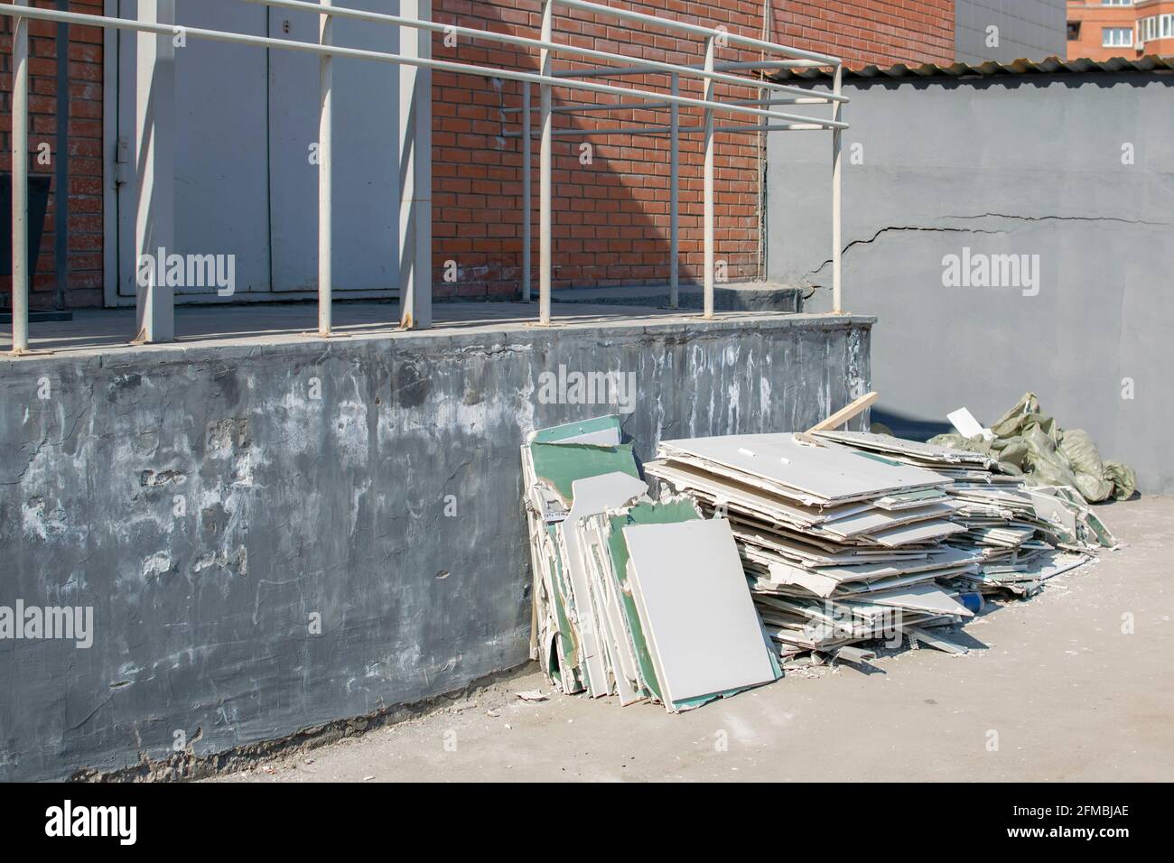 a pile of construction debris, broken drywall, lies near a brick ...