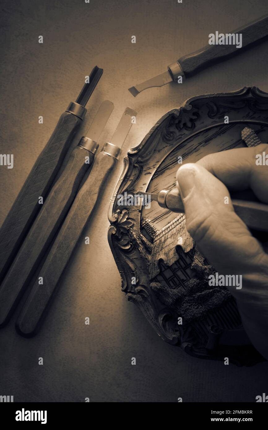 Man carving wood with chisels, making wall art plaque. With colour ...