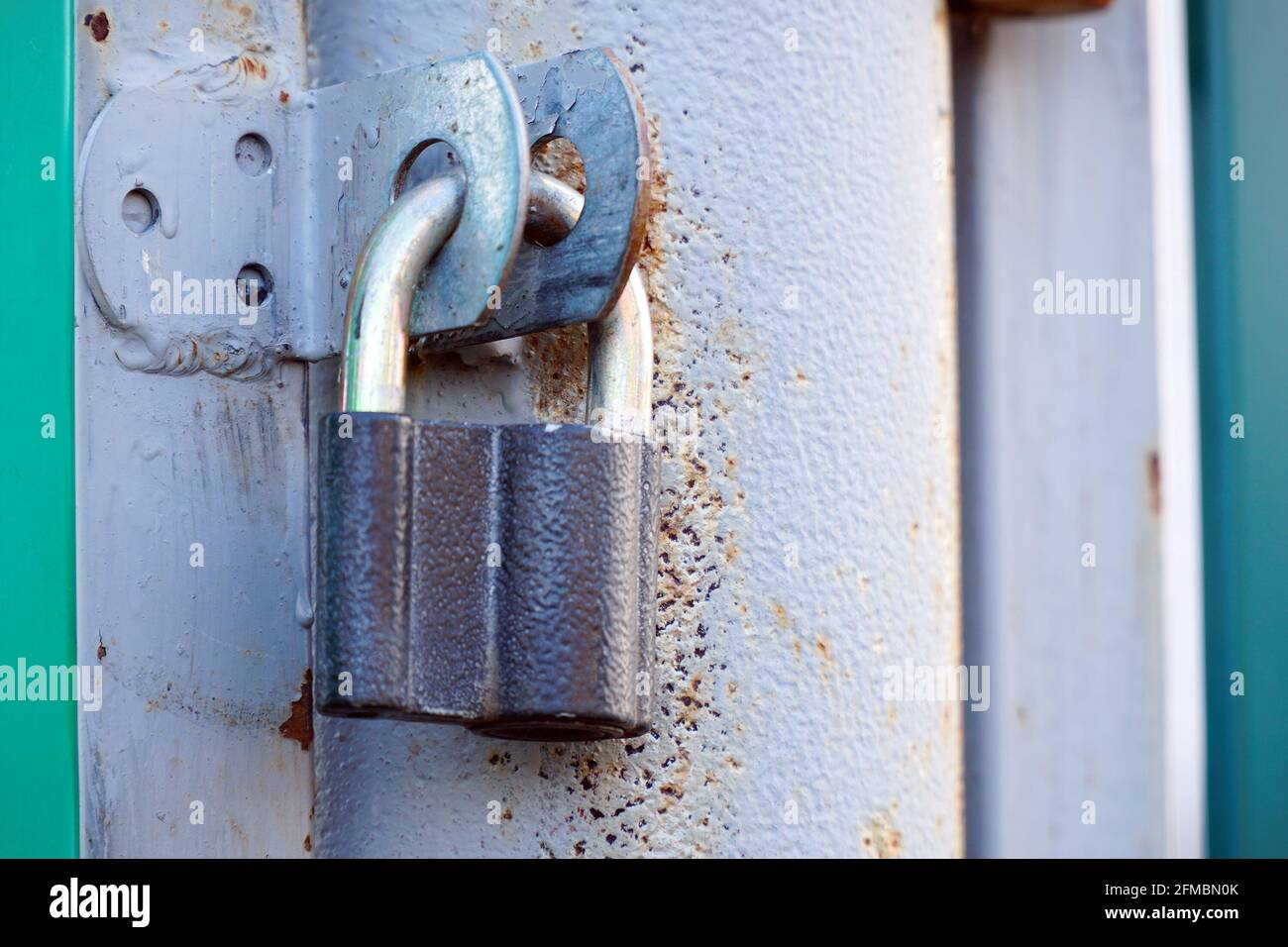 Closed padlock hanging on the hinges on the gray iron door Stock Photo ...