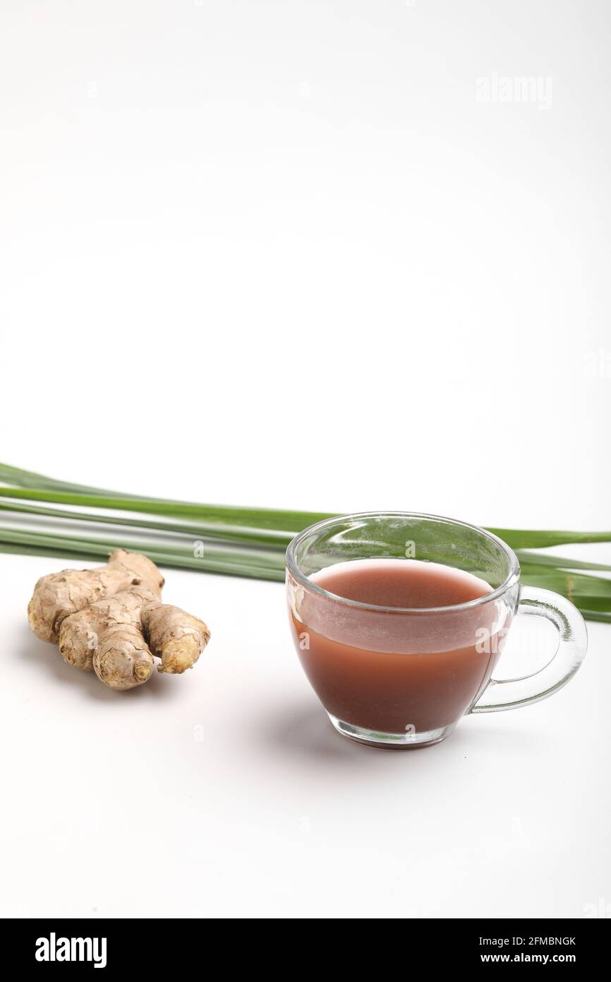 Glass cup of hot ginger tea with ginger rhizome (root) sliced on white ...