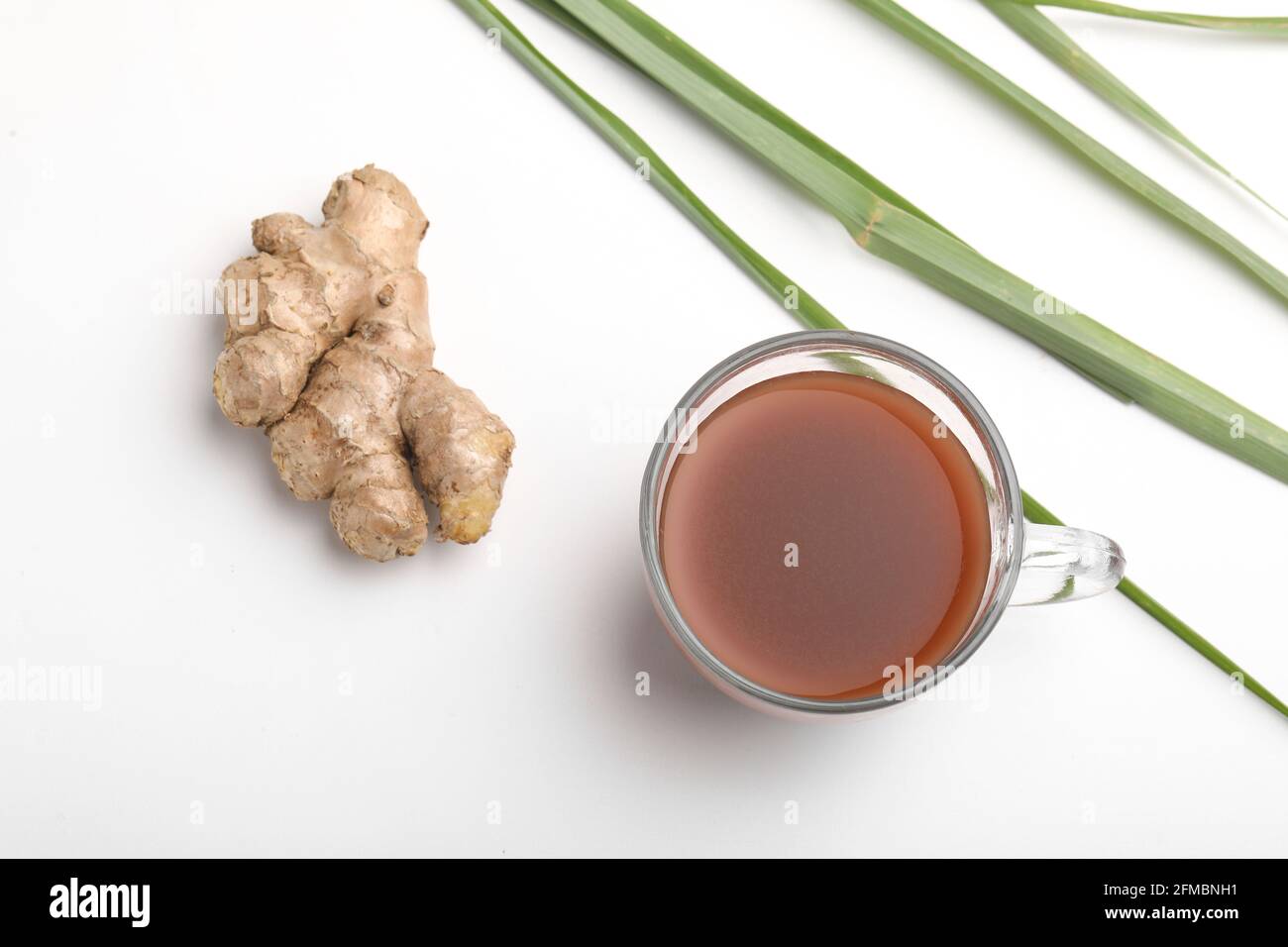 Glass cup of hot ginger tea with ginger rhizome (root) sliced on white ...