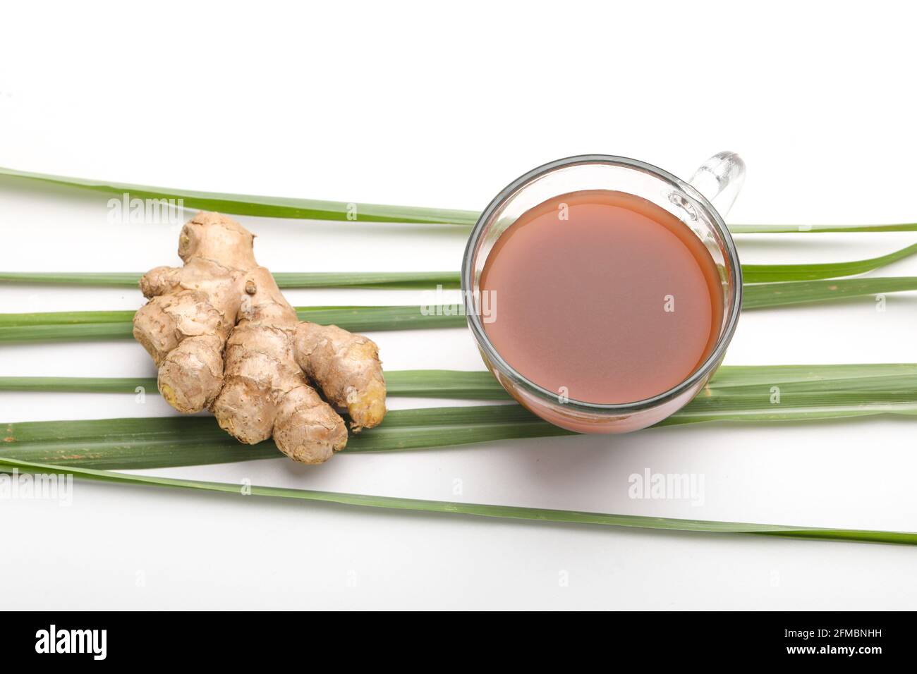 Glass cup of hot ginger tea with ginger rhizome (root) sliced on white ...