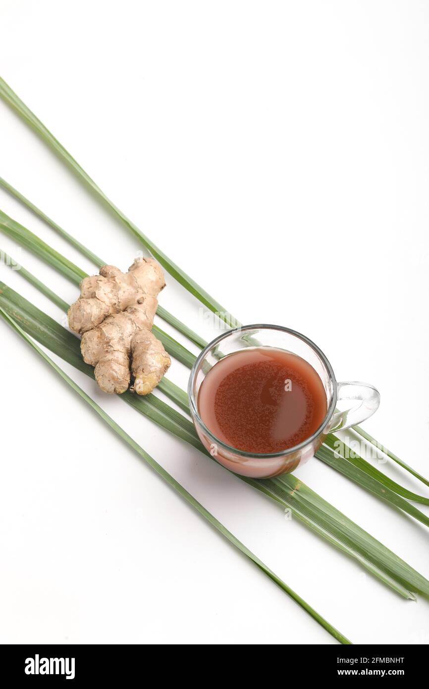 Glass cup of hot ginger tea with ginger rhizome (root) sliced on white ...