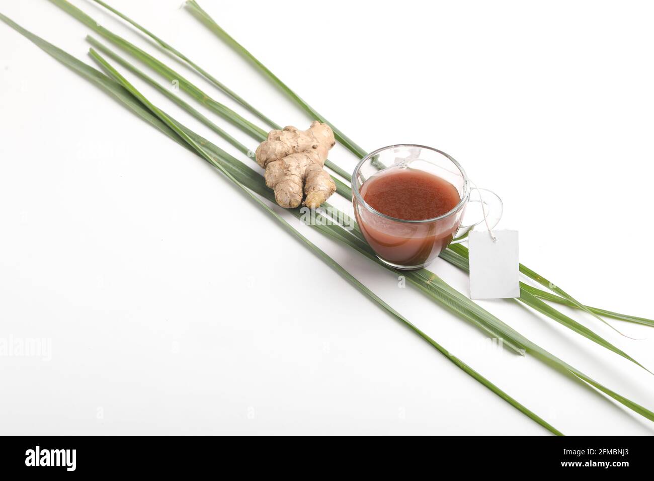 Glass cup of hot ginger tea with ginger rhizome (root) sliced on white ...